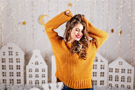 Free Photo Cute Shy Girl Modestly Smiles And Poses With Raised Arms In Cozy Interior