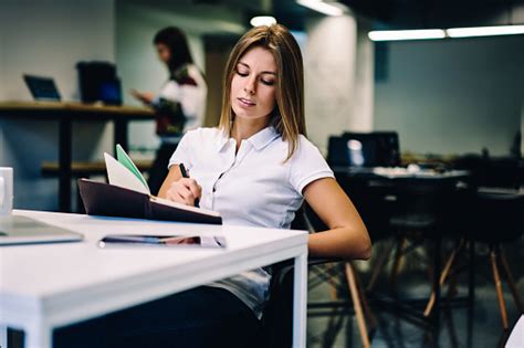 대학 도서관의 테이블에 앉아 메모장에 숙제 작업을 쓰고 공동 작업에서 시간을 보내는 아이디어에 대해 생각하는 노트를 만드는 출판의 창조적 인 여성 저자 집중 여성 계획에