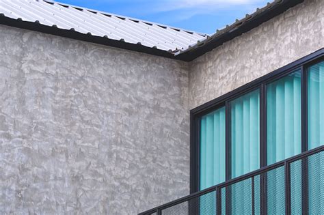 파란색 커튼이 있는 유리 슬라이딩 도어와 콘크리트 로프트 벽이 있는 발코니에 메쉬 강철 난간과 산업 스타일의 현대 주택의 골판지 금속 지붕 0명에 대한 스톡 사진 및 기타