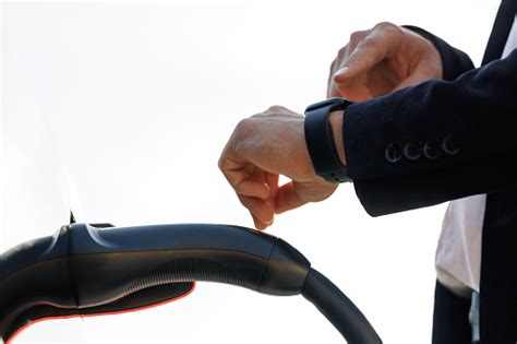 인식 할 수없는 남성 손 삽입의 클로즈업은 Ev 자동차에 전원 커넥터를 삽입하여 스마트 워치를 사용하여 충전을 시작합니다 전기 자동차에 충전 Chademo 케이블 유형 2