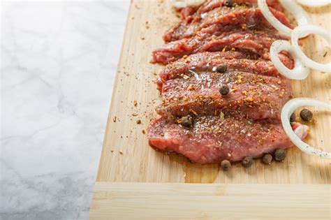 가벼운 질감의 배경에 향신료로 절인 양파를 곁들인 생 쇠고기 고기 요리법 대나무 판자에 육즙이 많은 스테이크 클로즈업 텍스트를위한 장소 복사를위한 공간 0명에 대한 스톡