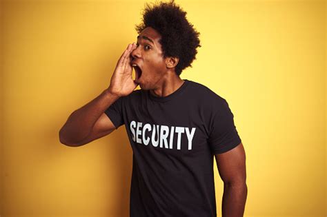 고립 된 노란색 배경에 보안 유니폼을 입고 아프로 머리를 가진 미국의 보호 대위 남자는 입에 손으로 옆으로 큰 소리로 외치고 비명을 지르고 있습니다 통신 개념입니다 감시에