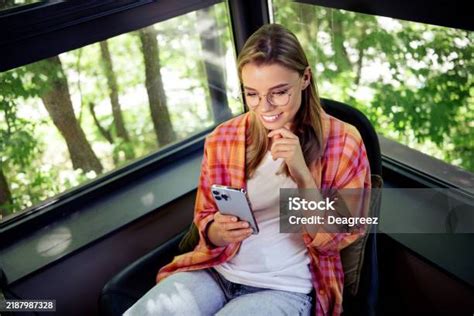 예쁜 젊은 금발 소녀 호기심 보류 장치 착용 격자 무늬 셔츠 앉아 테이블 카페 도서관 작업장 내부 큰 창문 나무 공원 전망 등의 사진 25 29세에 대한 스톡 사진 및 기타