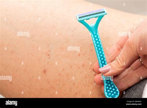 Close Up Picture Of Woman Holding Razor Shaving Her Hairy Leg With
