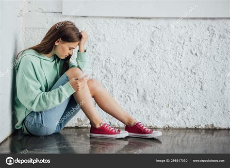 Sad Girl Sitting Against Wall