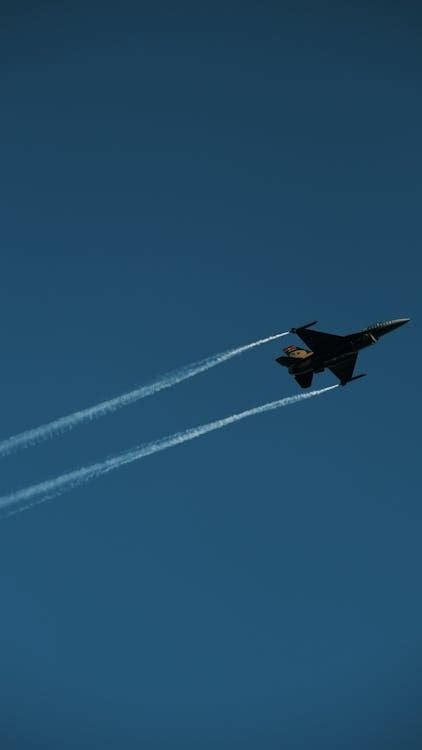 Avion De Chasse En Vol Avec Des Traînées De Condensation Dans Un Ciel Dégagé · Photo Gratuite