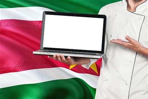 수리남 국기 배경에 빈 화면으로 노트북을 들고 수리남 요리사 복사 공간에 대 한 유니폼과 포인팅 노트북을 입고 요리 고급 요리에 대한 스톡 사진 및 기타 이미지 Istock