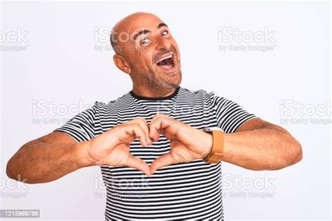 중년 잘생긴 남자는 손으로 심장 기호 모양을하고 사랑에 미소 고립 된 흰색 배경 위에 줄무늬 네이비 티셔츠를 입고 로맨틱 한 개념 T 셔츠에 대한 스톡 사진 및 기타 이미지