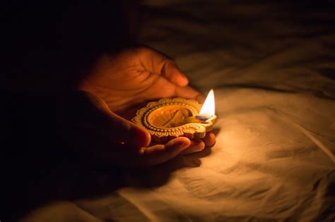 축제 축하 기간 동안 빛나는 불꽃으로 만든 디왈리 디야 또는 인도 전통 오일 램프를 들고 손을 들고 있습니다 복사 공간이 있는 어두운 배경입니다 Kali Puja에 대한