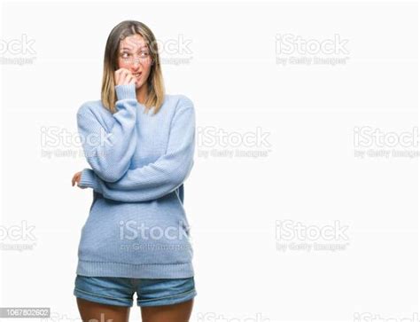 강조 하 고 손톱을 물어 뜯고 입에 손을 긴장을 찾고 격리 된 배경 위에 겨울 스웨터를 입고 젊은 아름 다운 여자 불안