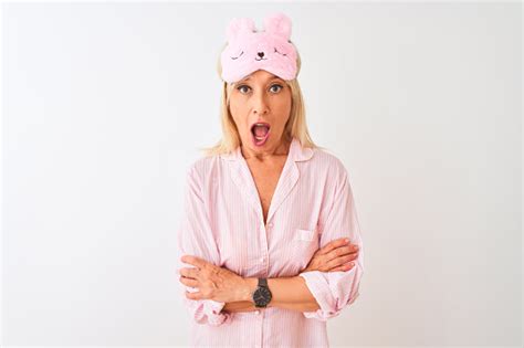 고립 된 흰색 배경 위에 수면 마스크와 잠옷을 입은 중년 여성은 놀라움의 표정 두려움 흥분된 얼굴로 충격을 받았습니다 감정에 대한 스톡 사진 및 기타 이미지 Istock