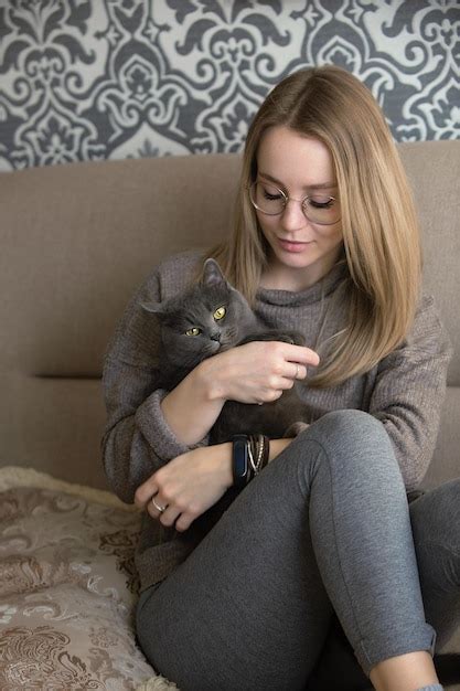 Premium Photo Beautiful Girl Sits At Home On The Sofa And Hugs Her