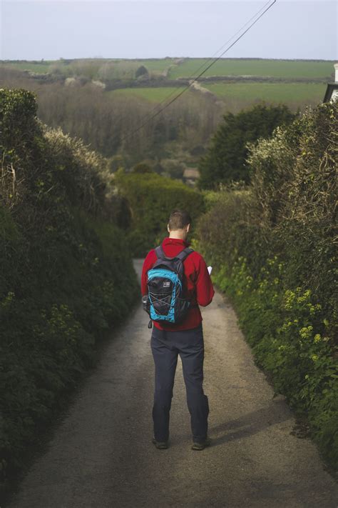 낮 동안 회색 콘크리트 도로에 서 있는 빨간색과 검은색 재킷과 검은색 바지를 입은 남자 사진 Unsplash의 무료 지도 읽기 이미지