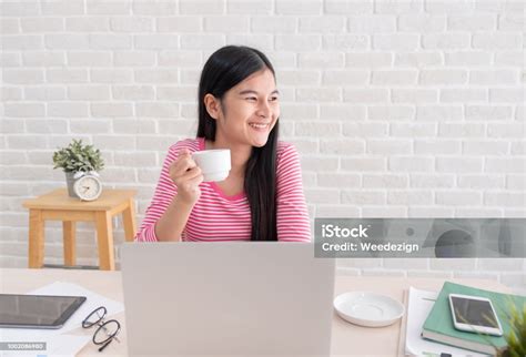 아시아 여성 프리랜서 미소와 음료와 커피 휴식 감정과 Homeworking 온라인 라이프 스타일에서 벽돌 벽에 테이블에 노트북 작업에서 창 걸릴 Breake에서 찾고 가정