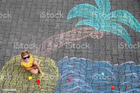 바다 모래 아스팔트에 화려한 분필로 칠해진 손바닥으로 수영복을 입은 행복한 어린 미취학 소녀 분필 그림으로 재미있게 지내는 귀여운 아이 여름 휴가 여름 공기 주입에 대한