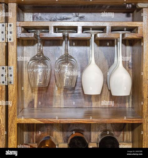 Tall Stemware Glasses Hanging Upside Down In Wooden Cabinet Storage