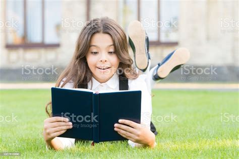 정보 없이는 진실이 없을 수 있습니다 작은 아이는 도서관 책에서 정보를 가져옵니다 귀여운 어린 소녀는 녹색 잔디에 읽습니다 학교 정보 교육 및 정보 9월에 대한 스톡 사진
