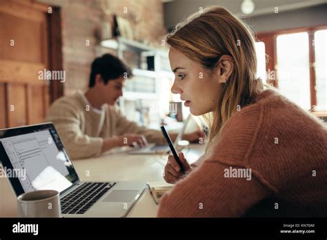 Woman Looking At Laptop For Making Notes With Her Babefriend Working On Laptop In Background
