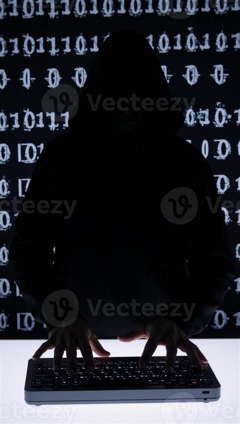 A Hooded Criminal Silhouetted While Hacking On Binary Code Background