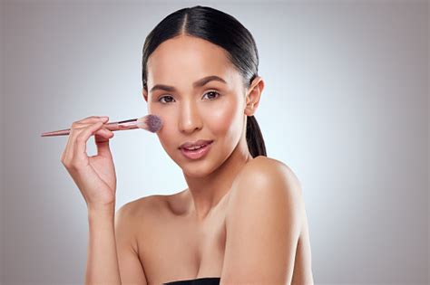 회색 배경에 브러시로 얼굴에 메이크업을 적용하는 아름다운 젊은 여성의 스튜디오 초상화 20 24세에 대한 스톡 사진 및 기타 이미지 20 24세 20 29세 가꿔주기