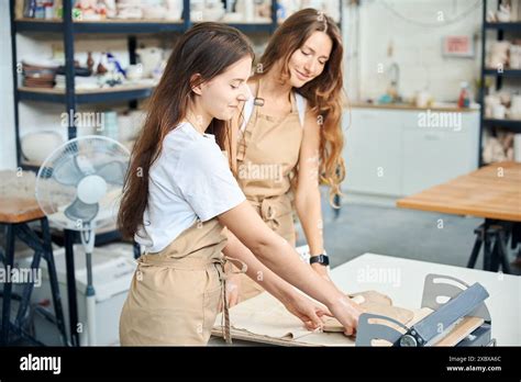 Women Working Potters Rolling Out Clay Slabs Together In Pottery Studio