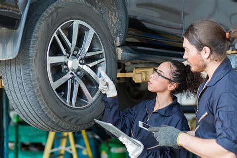 자동차 수리 점에서 남성 및 여성 자동차 정비사 직원 확인 수리 및 유지 보수 휠 차고에서 휠 타이어를 검사하는 정비사 차량 서비스 유지 보수 그룹 자동차 수리 서비스