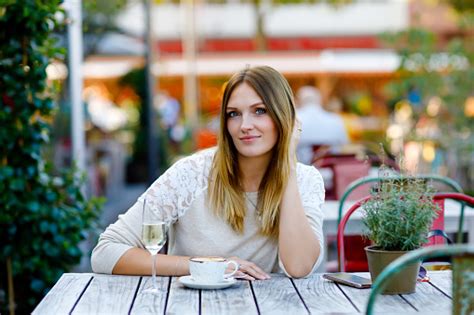 친구와 아침 식사를 기다리는 동안 카푸치노와 커피와 유리 샴페인 한 잔을 마시는 젊은 아름다운 여성 화창한 여름 날에 야외 카페 나 레스토랑에서 행복한 혼자 여성 대기에