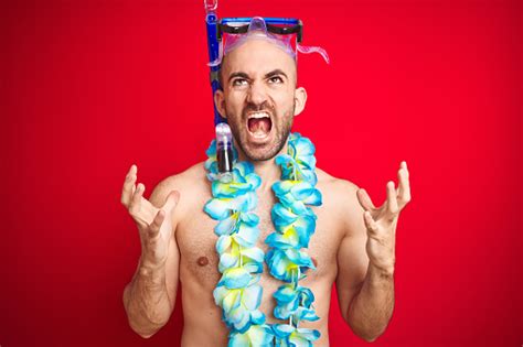 다이빙 스노클 링 고글과 하와이 레이 꽃을 입고 고립 된 빨간 배경에 미친 미친 미친 소리와 공격적인 표정과 팔을 들고 고함 좌절 개념입니다 남자에 대한 스톡 사진 및 기타