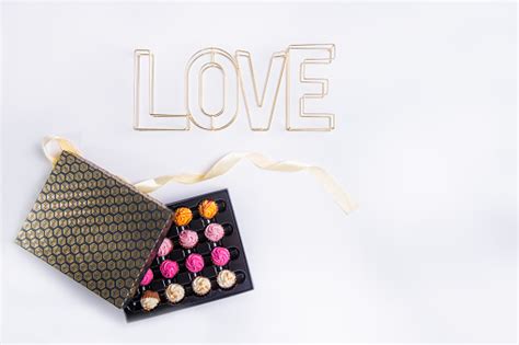 검은 색과 황금 상자의 상단보기 축제 구성은 여러 가지 빛깔의 크림 충전 및 와이어 단어 사랑 고립 된 모든 종류의 초콜릿 과자와 함께 해피 발렌타인 데이 공간을 복사합니다