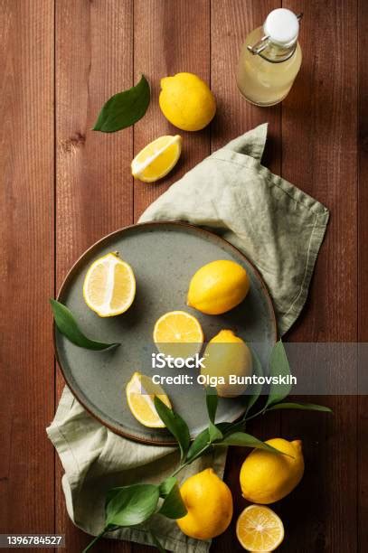 녹색 접시에 잎이있는 신선한 레몬과 어두운 나무 배경에 레몬 한 병이 마셔집니다 갓 짜낸 레모네이드를위한 감귤류 과일 어두운 구성과 소박한 스타일 위쪽 보기 0명에 대한