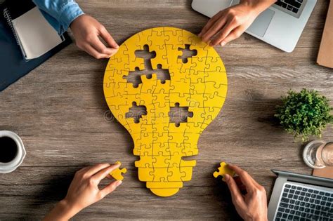 A Creative Brainstorming Session Depicted As Hands Assembling A Yellow Puzzle Shaped Like A