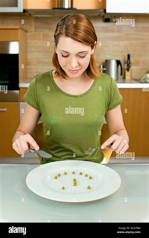 1223887 Indoor Flat Kitchen Young Woman Brunette 25 30 Green Blouse Sit Table Hold Knife Fork