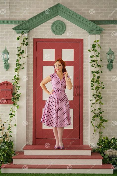 Beautiful Redheaded Pin Up Girl In Pink Polka Dot Dress And Vintage Stockings Posing Near The