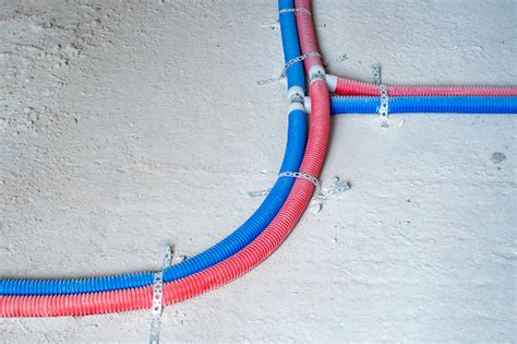 파란색과 빨간색 플라스틱 골판지 튜브가 바닥을 가로질러 뻗어 있습니다 건물의 수리 또는 건설 중에 열 및 물 공급의 임시 통신