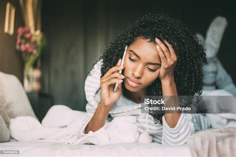 아름 다운 심각한 사려 깊고 슬픈 흑인 여성이 침대에 스마트폰을 사용 하 여 곱슬 머리를 가진 가정의 방에 대한 스톡 사진 및 기타 이미지 Istock