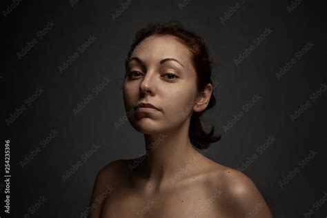 Portrait Of Tan Nude Woman Proudly Looks On A Camera Dark Background