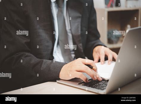 Man Person Using Keyboard Computer Laptop Holding Pen And Book On Desk Stock Photo Alamy