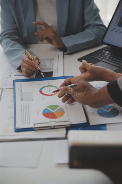 Close Up Of Business Team Analyzing Income Charts And Graphs With