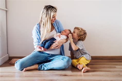 Una Madre Joven Hermosa Con Un Beb Reci N Nacido Y Su Hermano En Casa Foto De Archivo Imagen