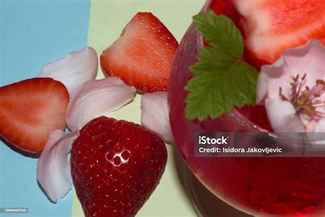 클로즈업하고 딸기 주스 한 잔에 딸기와 꽃 머리를 빨간색과 흰색으로 장식하고 파스텔 그린 블루 백그루드 목가적 인 여름에 딸기와