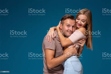 젊은 부부는 스튜디오에서 파란색 배경에 껴 안고 있습니다 그들은 T셔츠 청바지와 미소를 착용 합니다 2명에 대한 스톡 사진 및 기타 이미지 Istock
