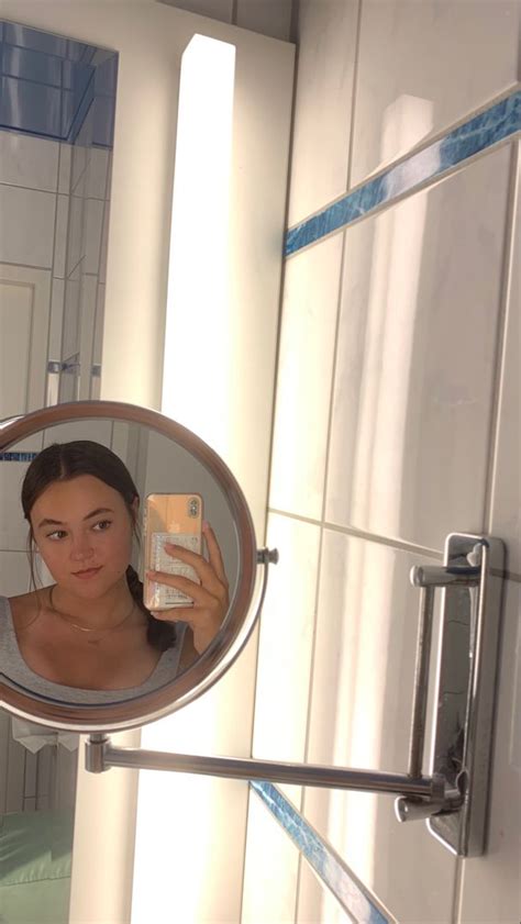 A Woman Is Taking A Selfie In The Bathroom Mirror With Her Reflection On The Wall