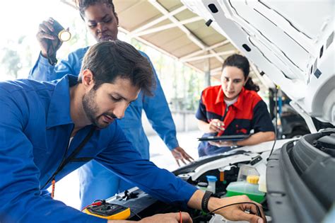 제복을 입은 정비사 남자가 고장난 전기 자동차로 작업합니다 작업장에서 일하는 동안 전기 자동차의 후드 자동차 서비스의 개념 전기 자동차 고정 에브 정비사가 수리 서비스에서