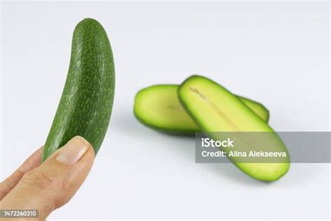 흰색으로 분리된 뒷면에 얇게 썬 칵테일 아보카도가 있는 미니 아보카도를 들고 있는 손을 닫습니다 건강한 삶을 위해 특별히 재배 된 이국적인 녹색 완전 채식 식품 기능성 식품