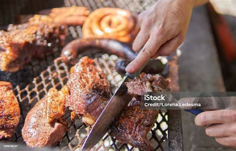점심 식사를 위해 바베큐를 만드는 남자의 손 고기 컷 바비큐 소시지와 피 소시지의 코일 철제 그릴에 쇠고기 전통적인 아르헨티나 바베큐 아사도 아르헨티노 바비큐에 대한 스톡