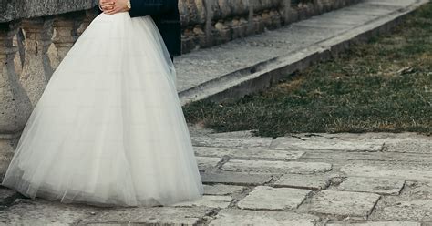 오래된 성을 배경으로 포옹하는 결혼식 커플 우아한 신랑 신부가 부드럽게 포옹 나비 넥타이를 맨 클래식 정장을 입은 남자와 진주가 달린 흰색 드레스를 입은 여자 텍스트