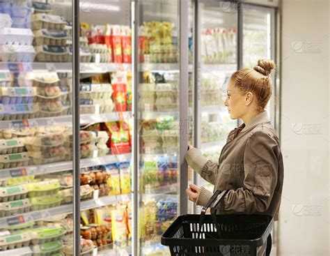 从超市冰箱里挑选冷冻食品的女人。