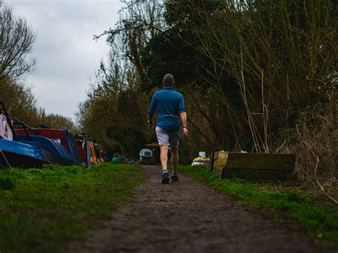파란색 티셔츠와 파란색 데님 반바지를 입은 남자가 낮에 갈색 나무 벤치에 서 있다 사진 Unsplash의 무료 사람 이미지