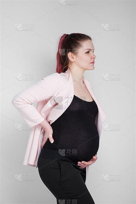 怀孕的女孩抱着她的背。疼痛，背部沉重。