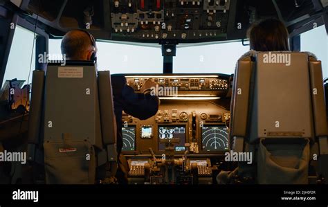 Captain And Woman Copilot In Cockpit Preparing To Fly Airplane Using Dashboard Command Buttons